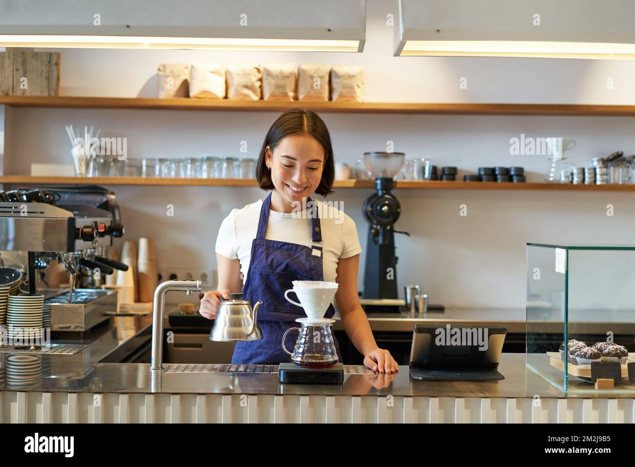 Smiling asian girl barista, working in cafe, brewing coffee v60 ...