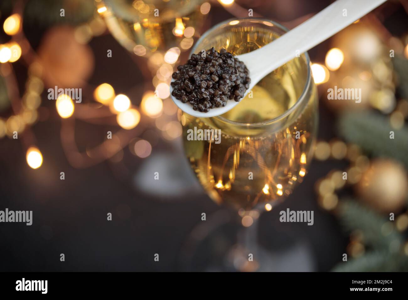 Black caviar in a mother-of-pearl spoon and glass of champagne with ...
