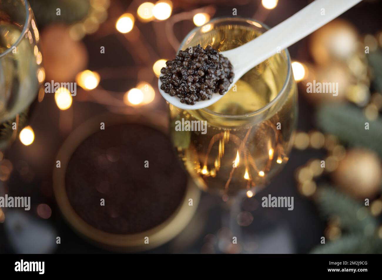 Black caviar in a mother-of-pearl spoon and glass of champagne with ...