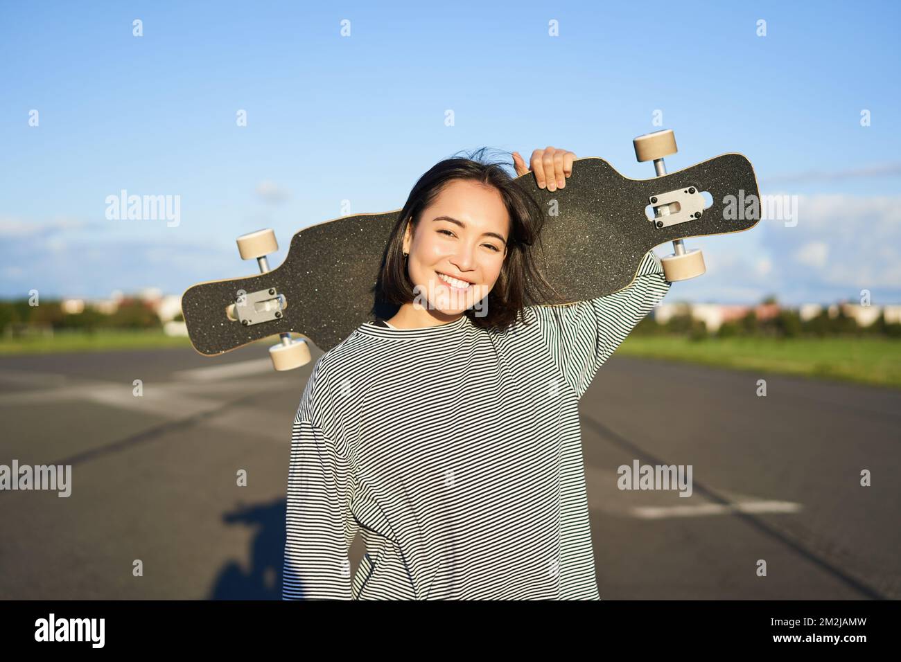 Leisure and people. Happy asian woman standing with longboard, cruising ...