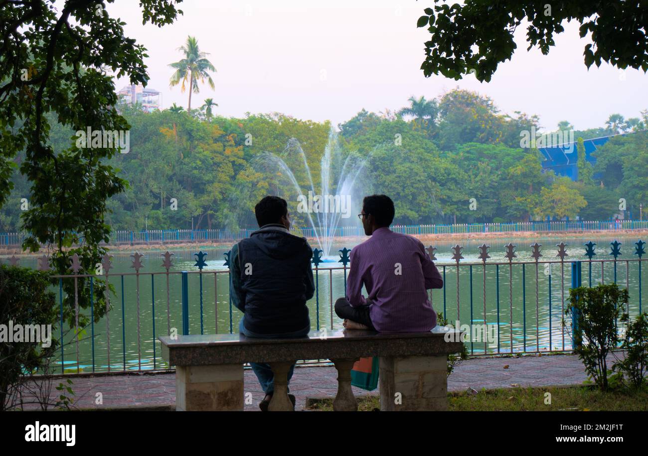 Two unidentified adult man on a park bench conversation or chatting on ...