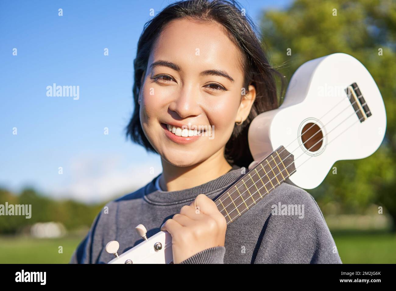 Portrait of beautiful smiling girl with ukulele, asian woman with ...