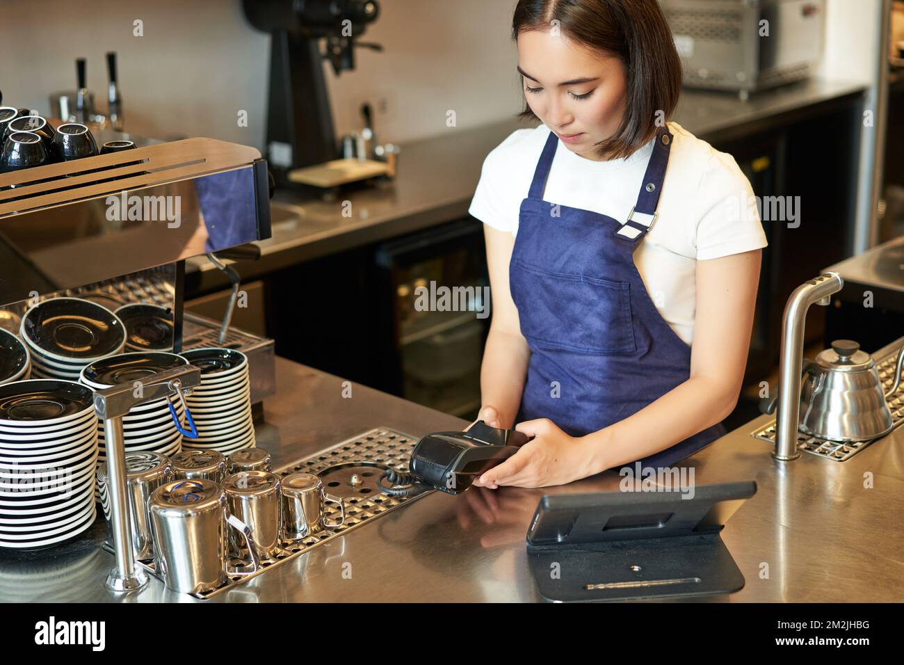 Smiling asian girl barista working in cafe at counter, processing ...