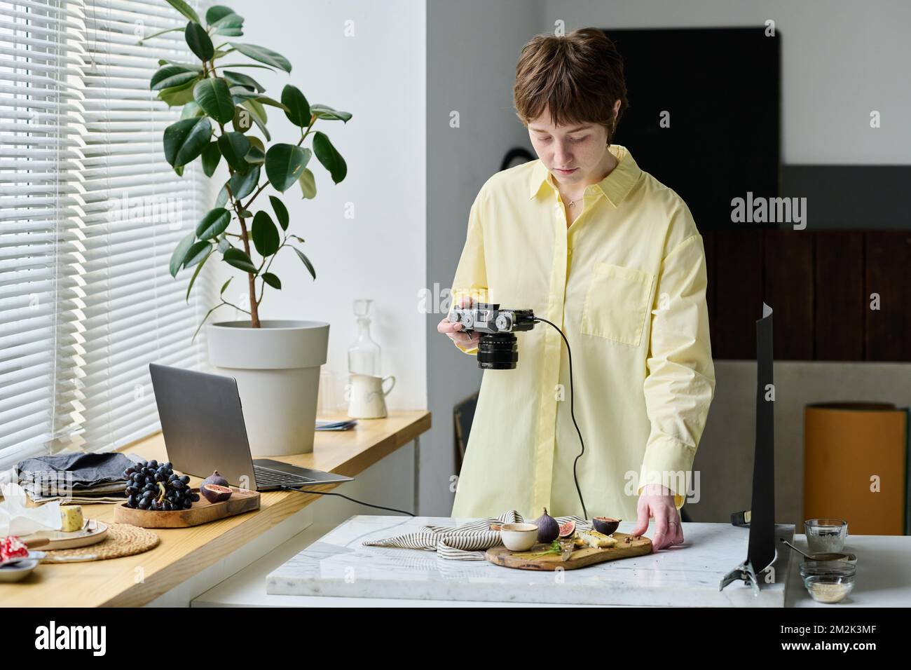 Young photographer making professional photos of food on wooden tray ...