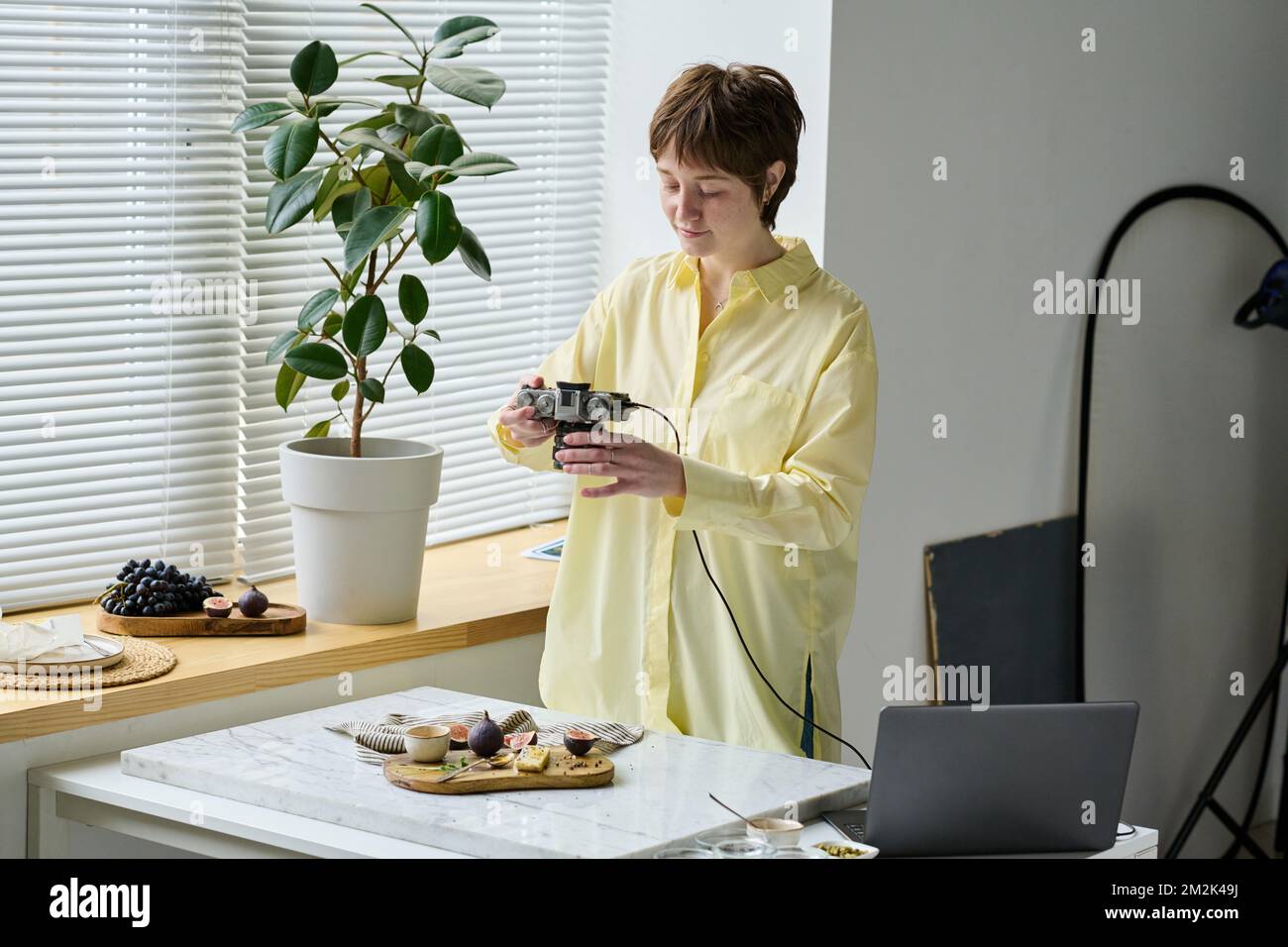 Young photographer using camera and laptop during her professional ...