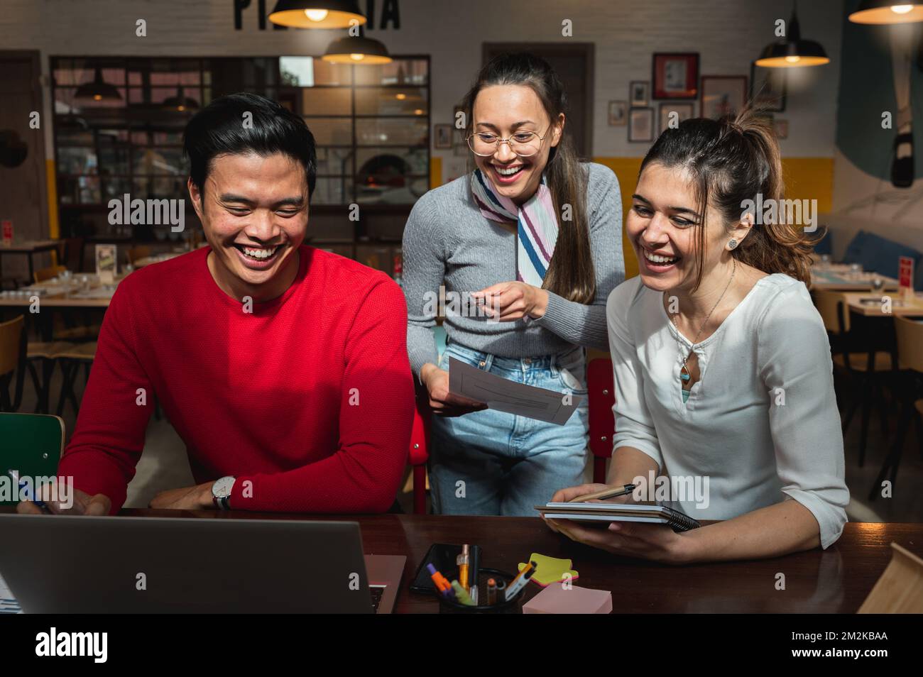 Multiracial group of three young people looking at computer laptop with ...