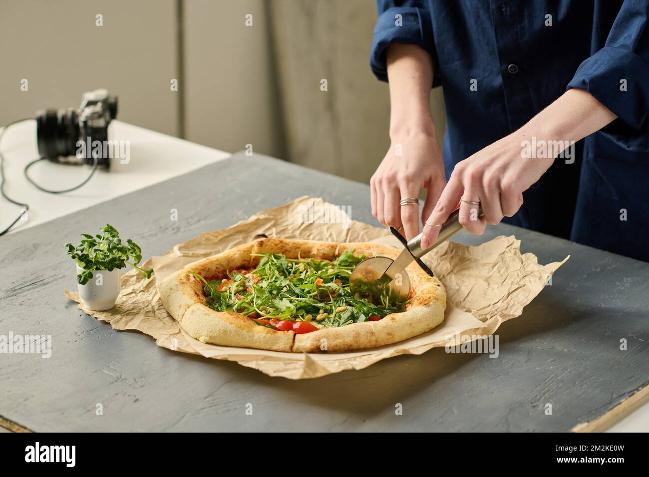 Close-up of female photographer cutting pizza with special knife for ...