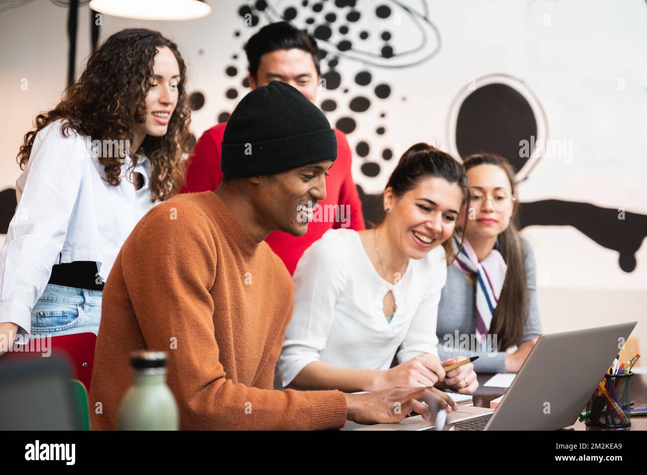 Mixed group of young smiling people looking at computer laptop with ...