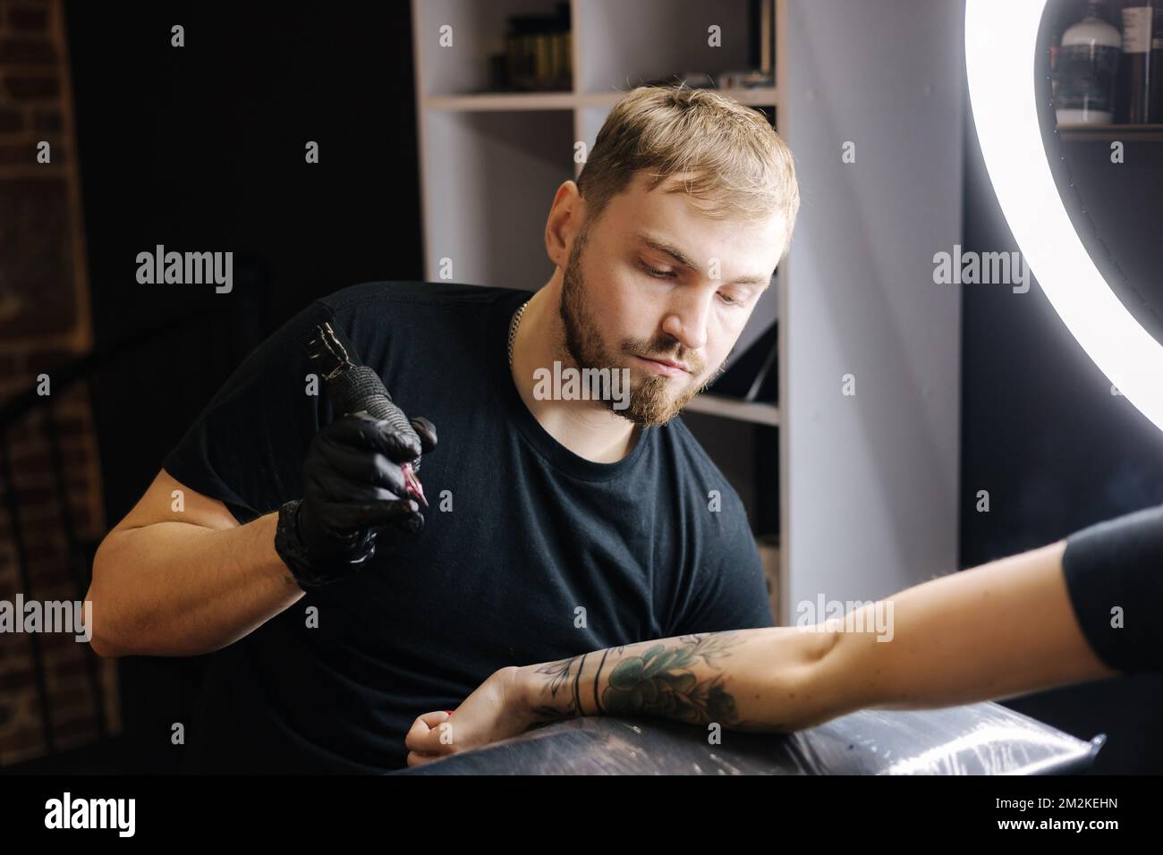 Tattoo master is tattooing a woman's hand. Wireless tattoo machine ...