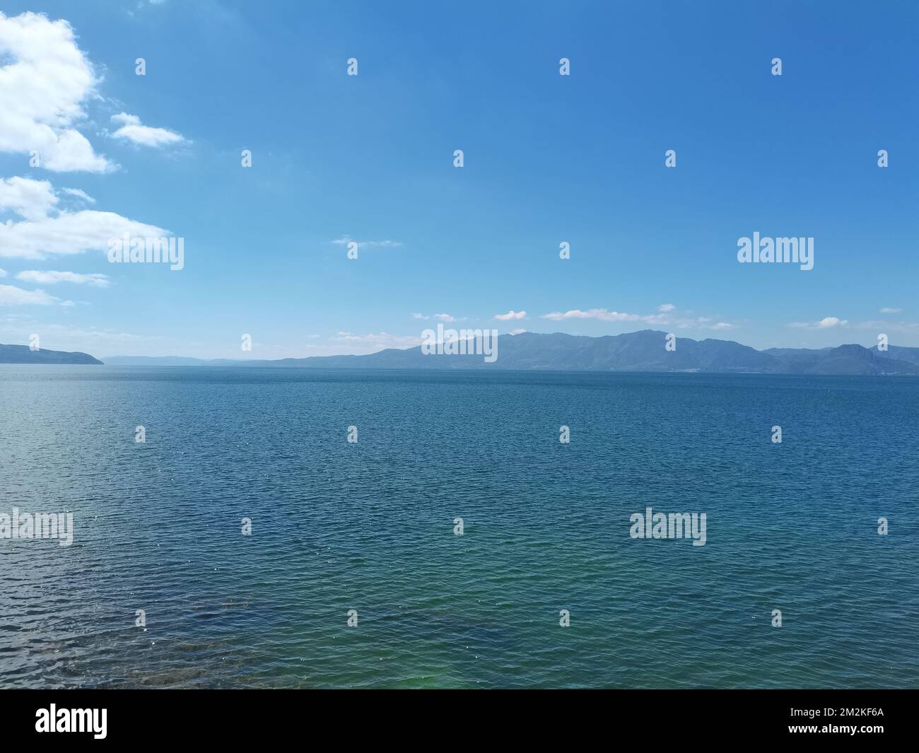 A breathtaking view of big blue lake under blue cloudy sky with ...