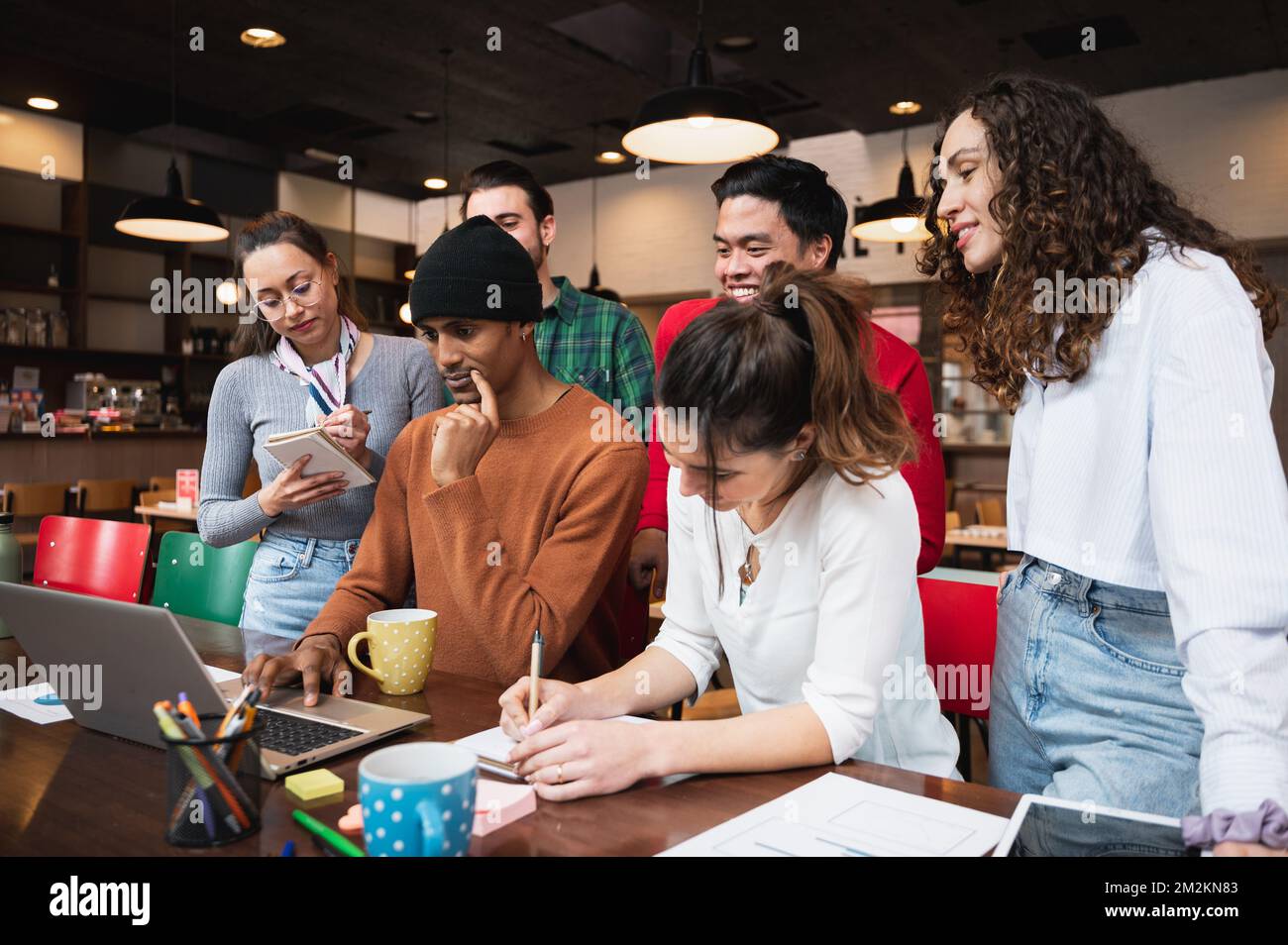 Multiracial mixed group of young people sitting at desk. Co-workers or ...