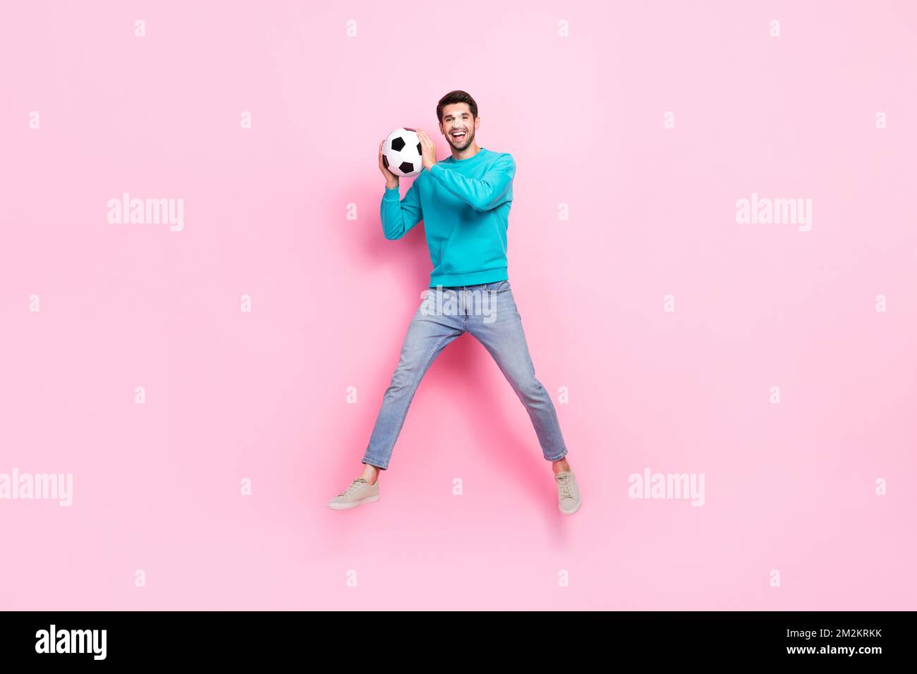 Full size photo of handsome young man jumping catch soccer ball ...