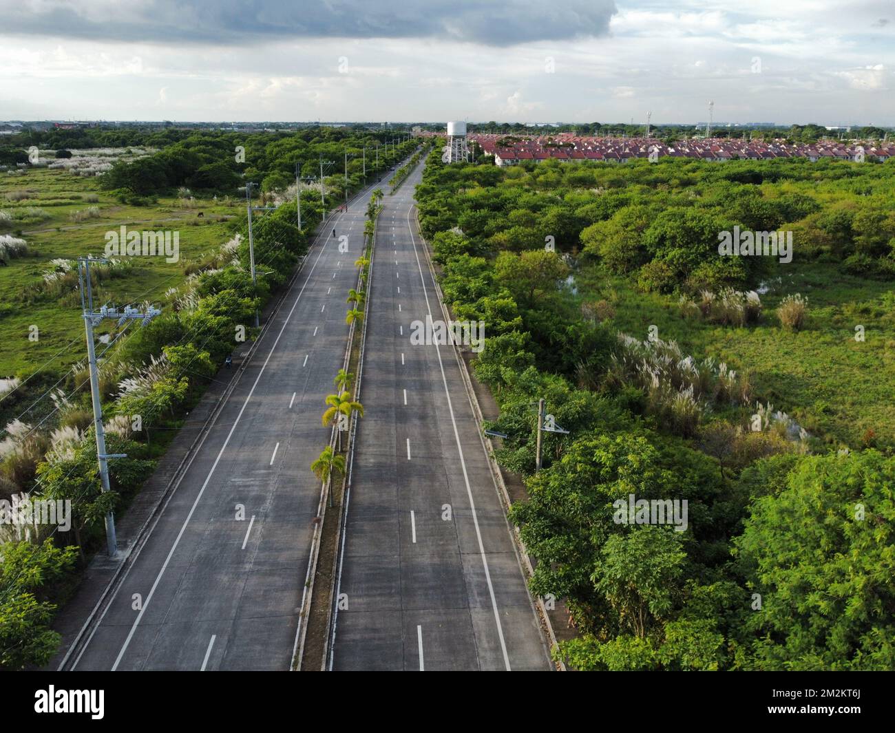 An aerial view of long asphalt highway between lush green rural fields ...