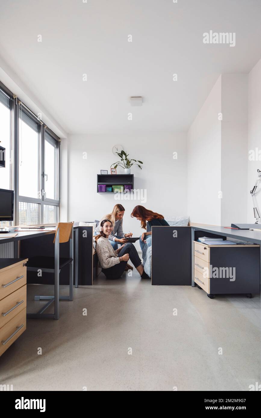 Vertical photo of three college students hanging out in their dorm room ...