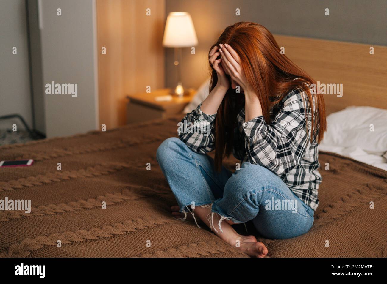 Upset sad red-haired woman suffering from loneliness, sitting in bed ...