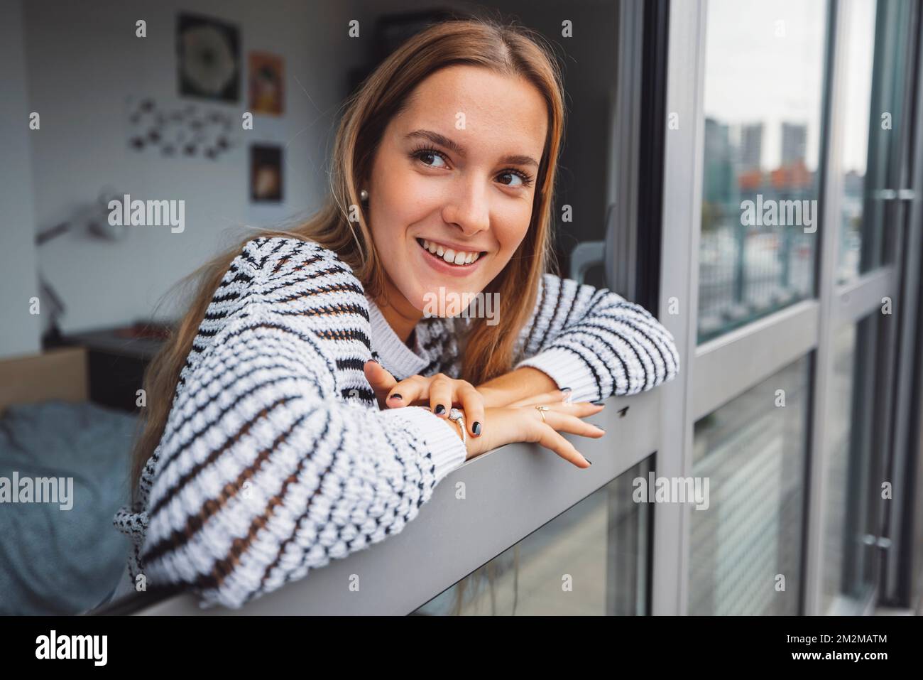 Smiling woman student looking out her dorm room window Stock Photo - Alamy