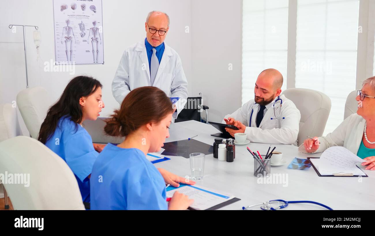 Female nurse taking notes while elderly medical expert explaining viral ...