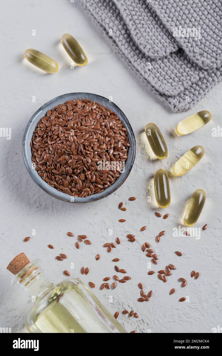 Brown flax seed or linseed in small bowl and gelatin capsules with ...