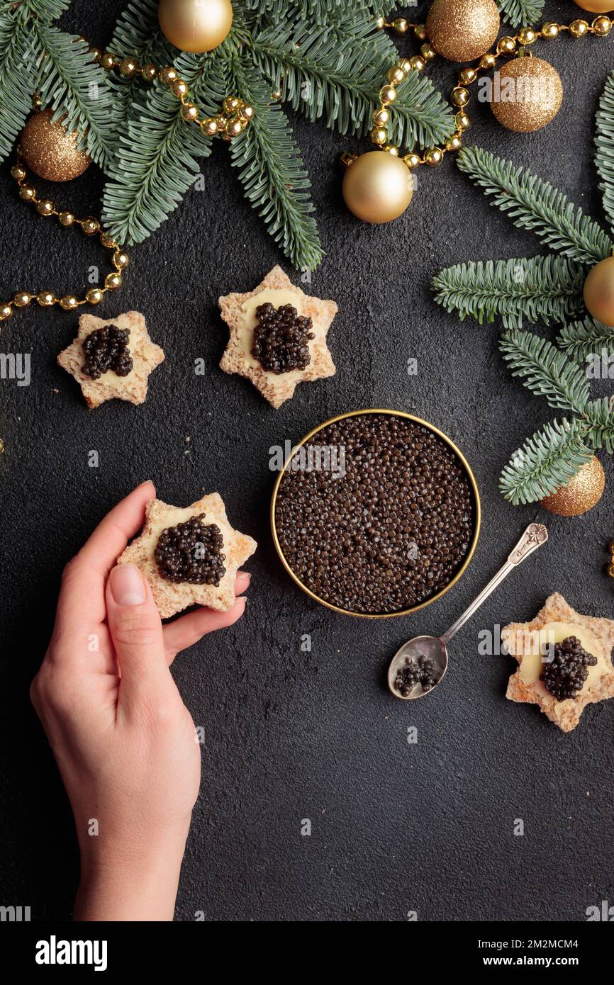 Black caviar appetizers stars in a human's hand on a christmas ...