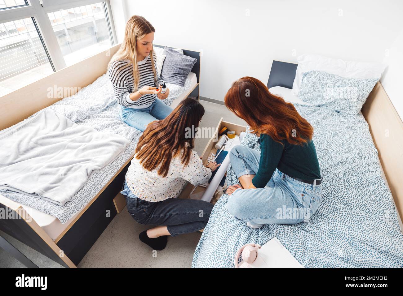 Group of three young college students in their dorm room doing arts and ...