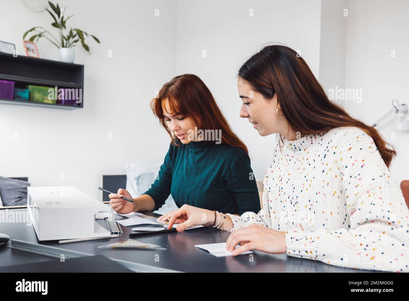 Two young architecture college students working on a project together ...