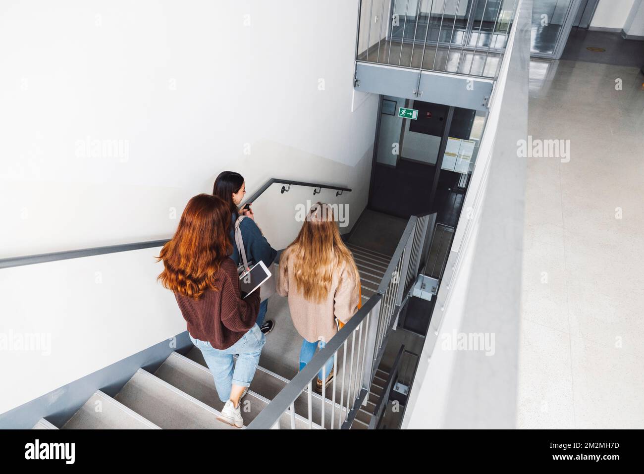View from the top of the staircase of three students walking down the ...