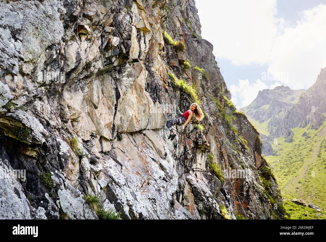 Portrait of Fit strong woman in red shirt and long hair climbing on the ...