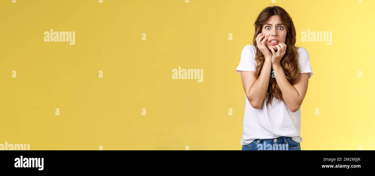 Worried insecure nervous european girl biting fingernails stare camera ...