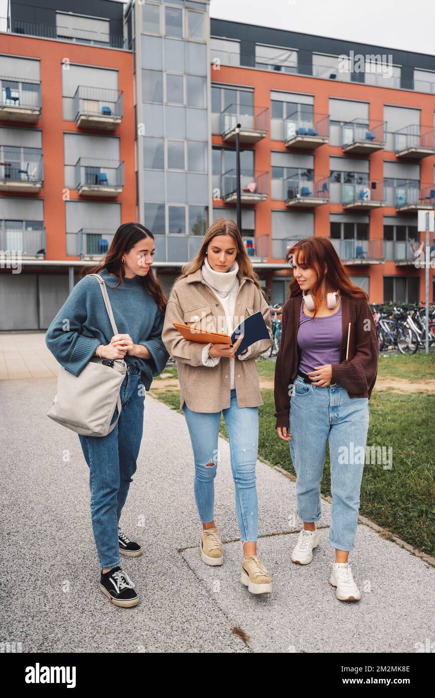 Vertical photo of three young woman standing outside in front of their ...