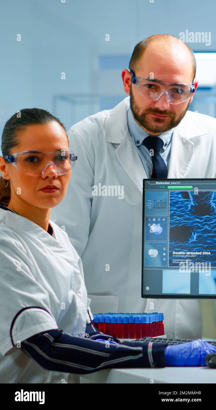Team of scientists sitting in laboratory looking at camera in modern ...
