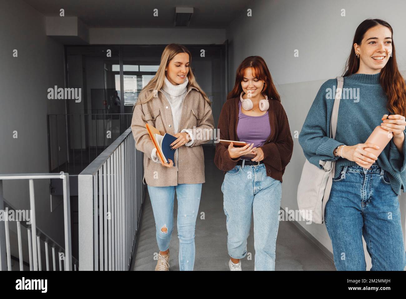 Three smiling college students on their way from dorm to the school ...