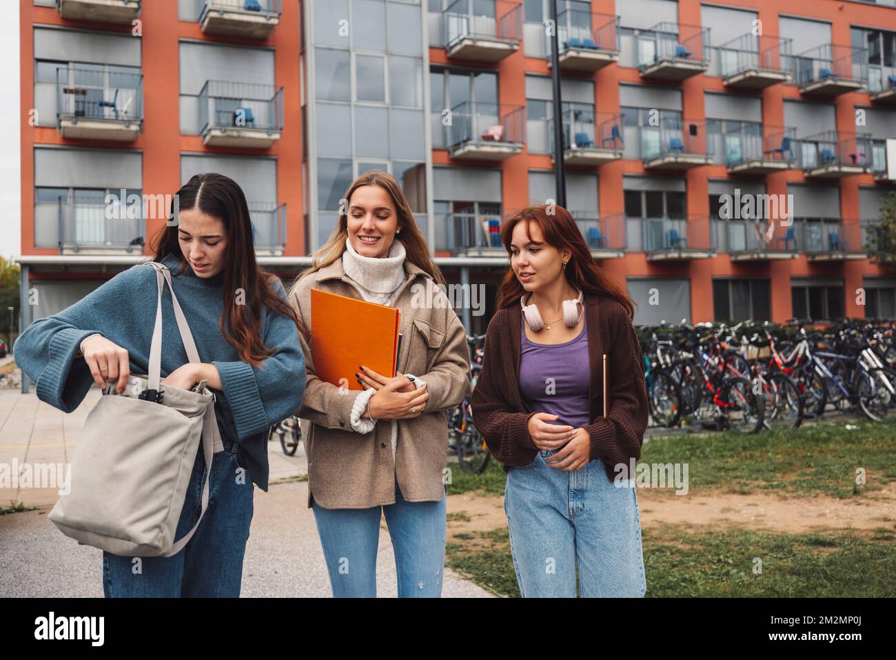 Three young woman students going to class together, walking side by ...