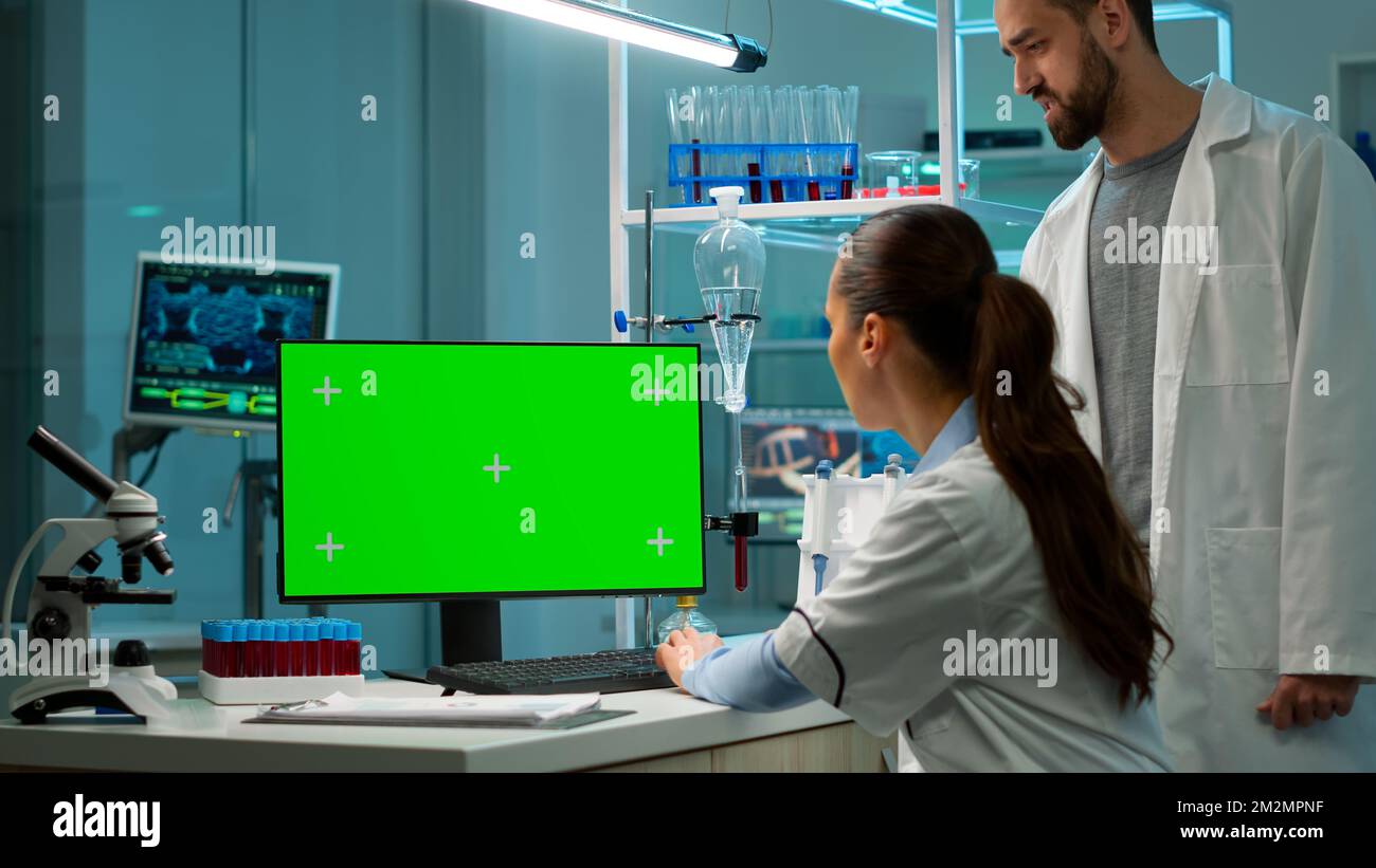 Female scientist working on computer with mock-up green screen in ...