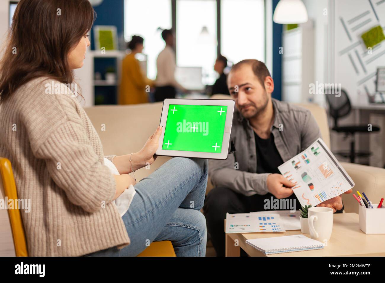 Over the sholder of manager woman sitting on couch talking with ...