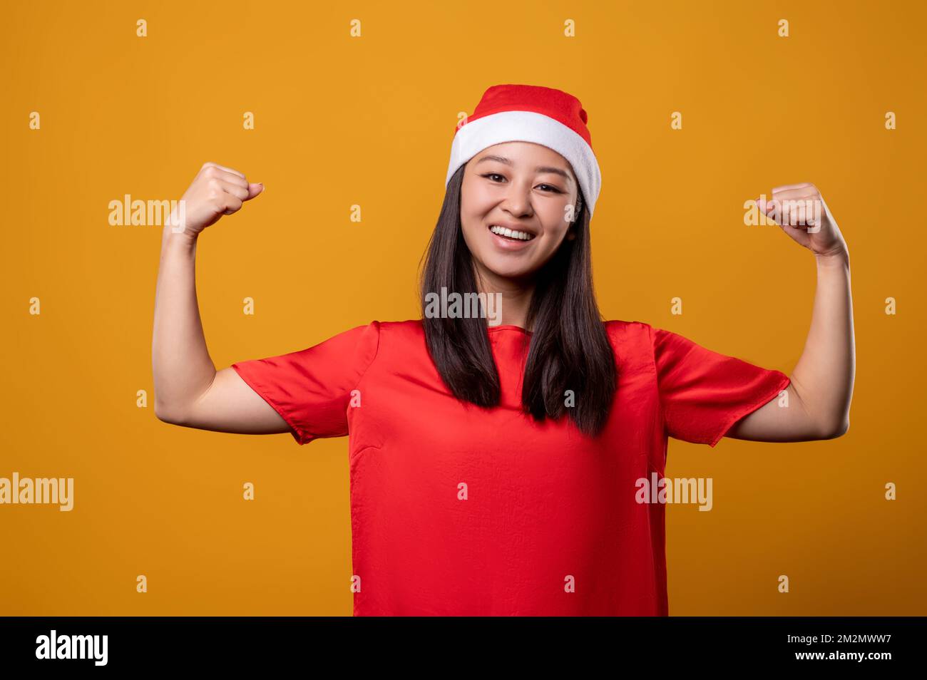 Cute young woman in red showing her muscles and looking determined ...