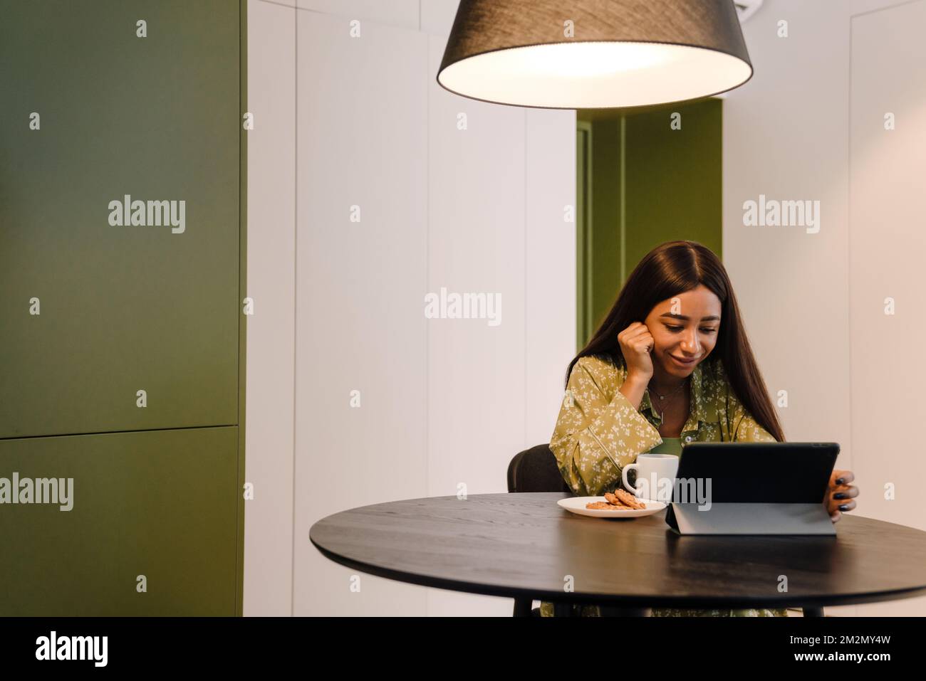 Young beautiful long-haired woman with cup of coffee with cookies ...