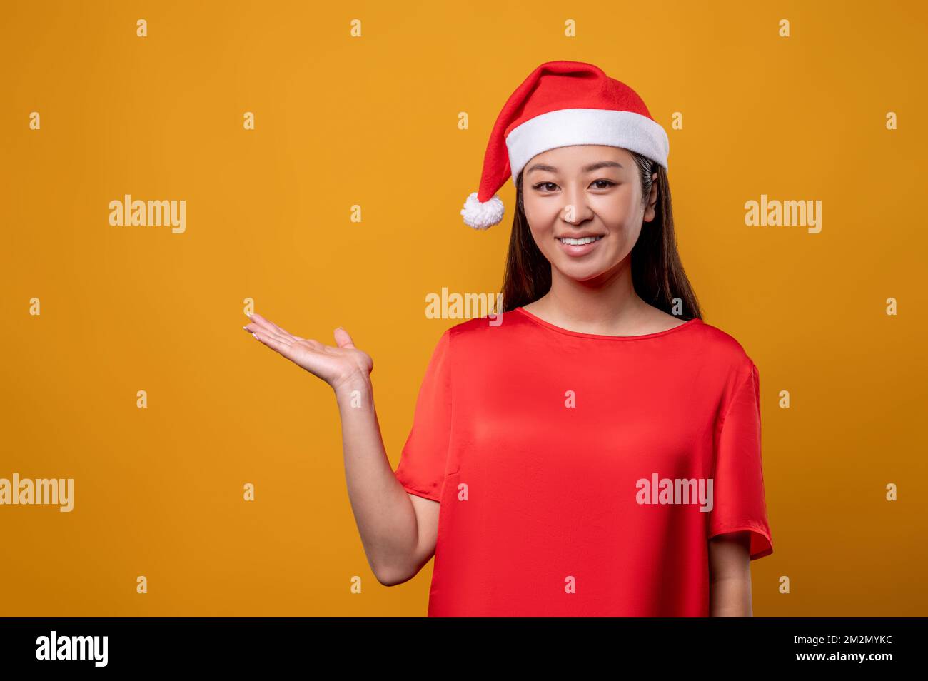 Cute young woman in santa hat on a yellow background Stock Photo - Alamy
