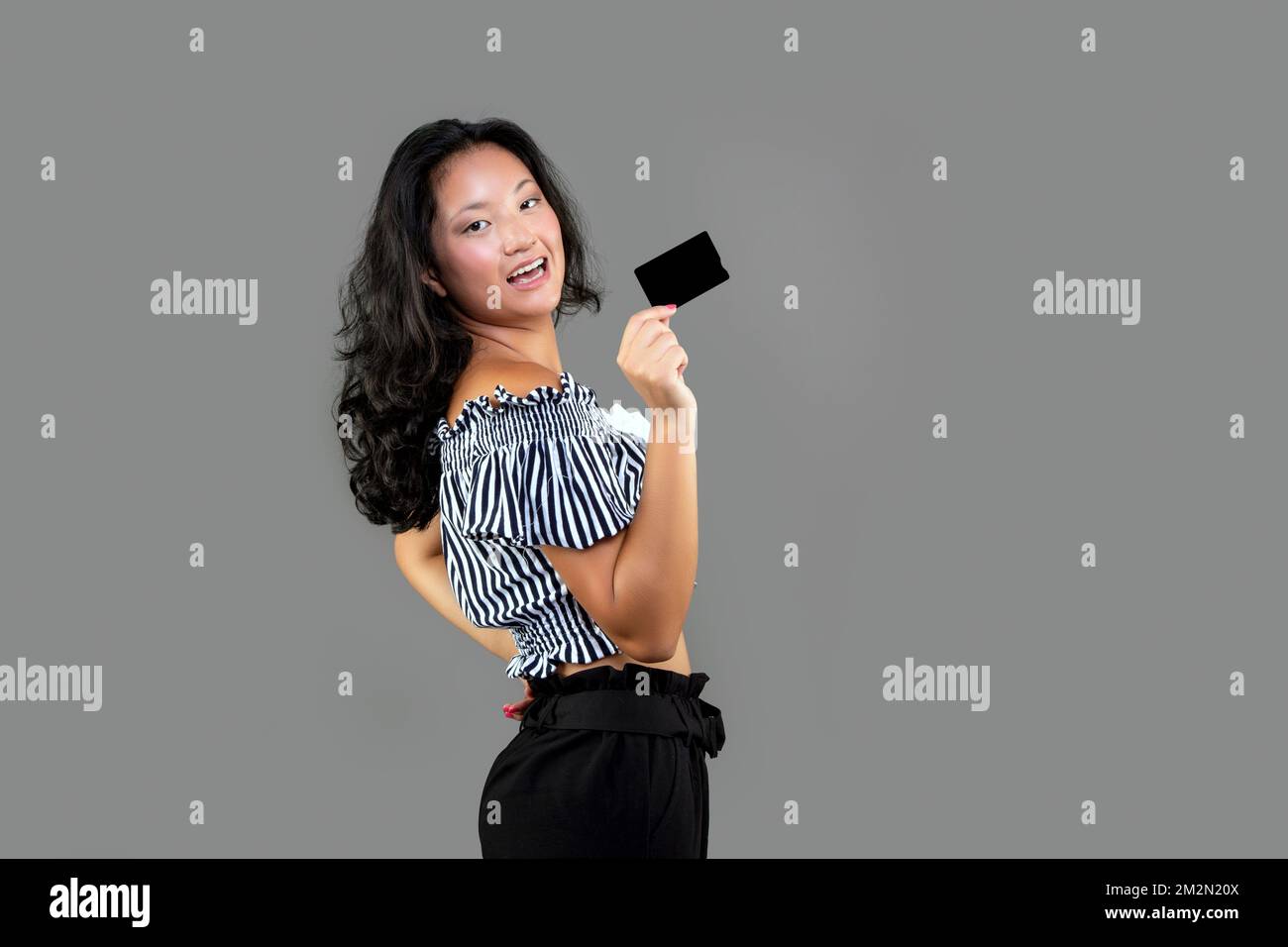 Pretty Asian girl with cute face showing a black card in her hand ...