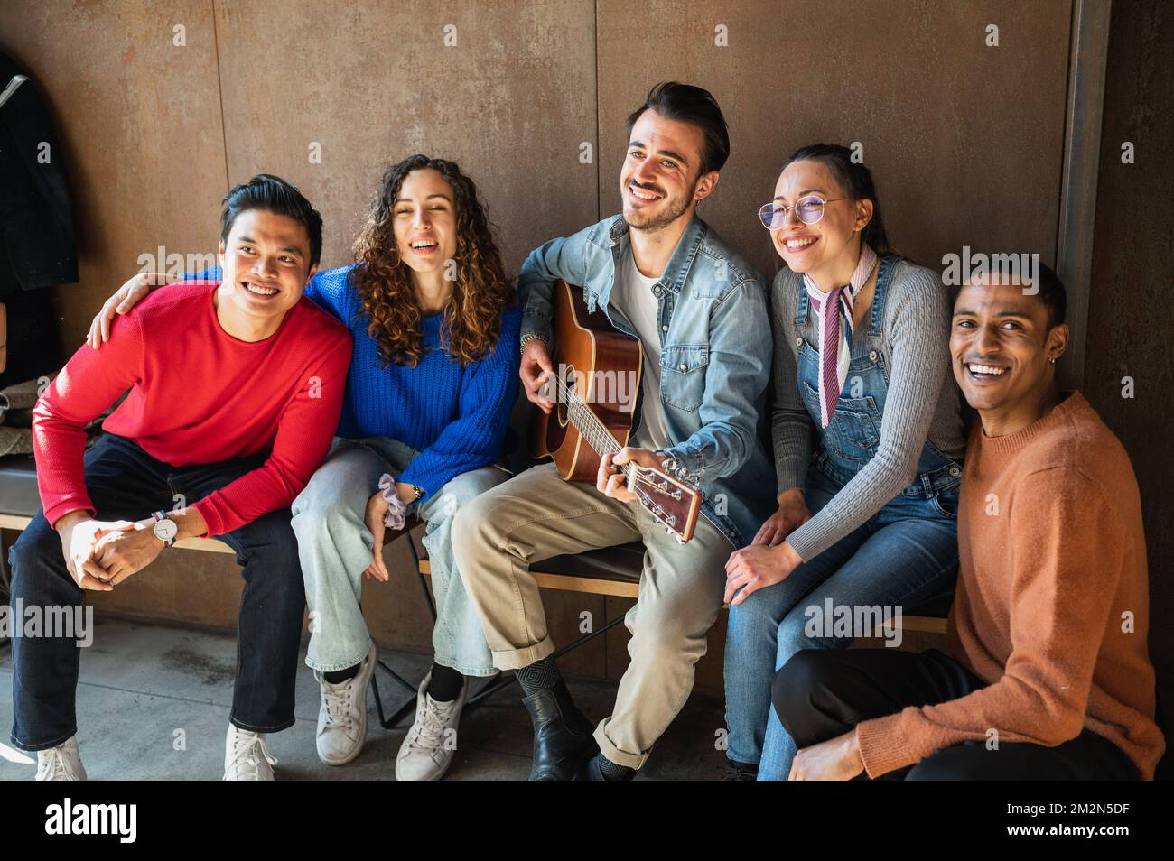 Multiracial group of young friends sitting indoor and enjoying playing ...