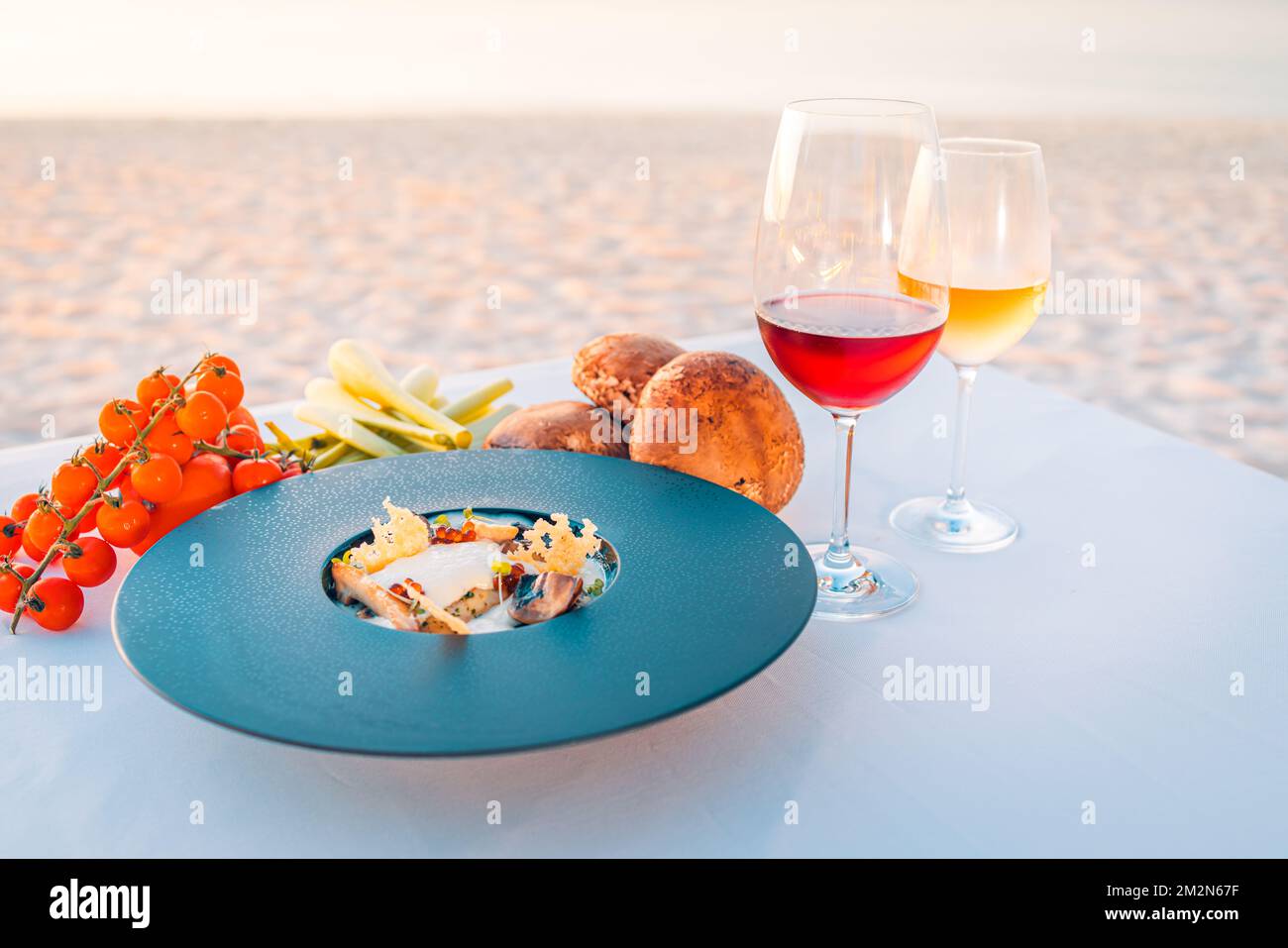 Sunset appetizer with wines and fresh vegetables on beach dinner table ...