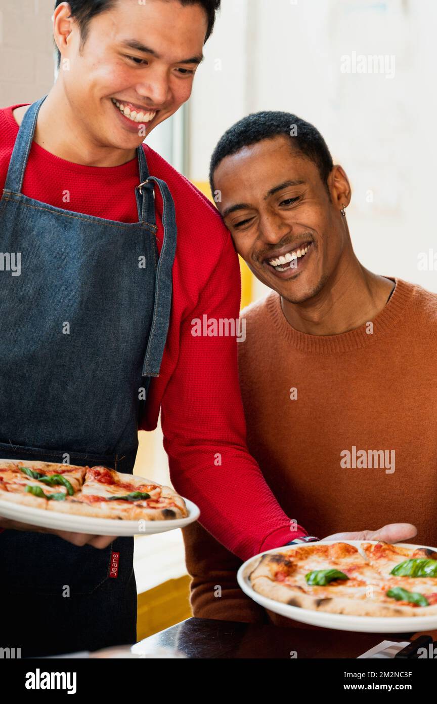 Vertical portrait African man smiling while looking at pizza served by ...