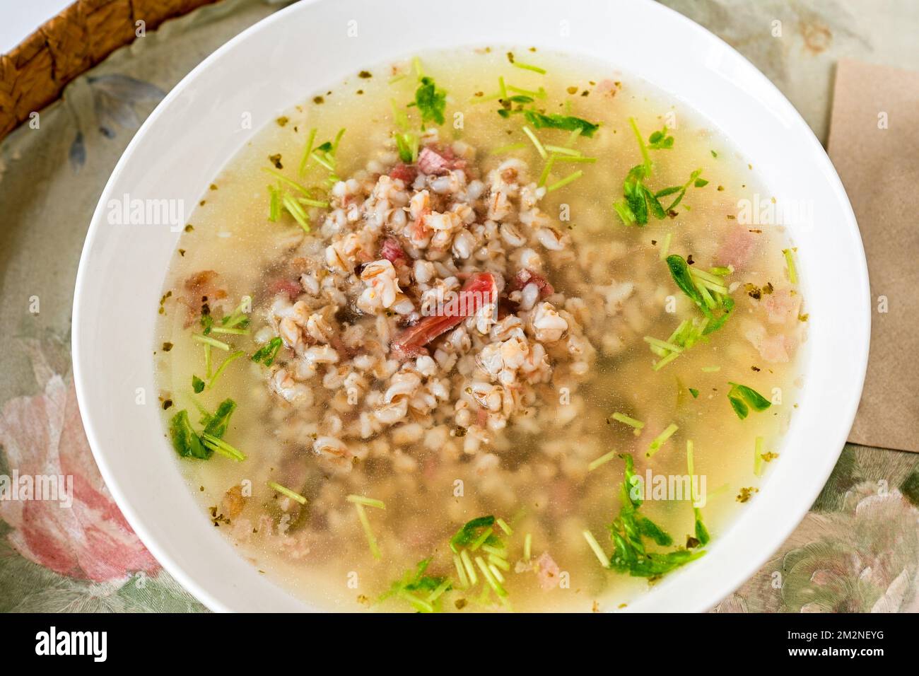 Soup with many groat, smoked meat piece and pea sprout in white plate ...