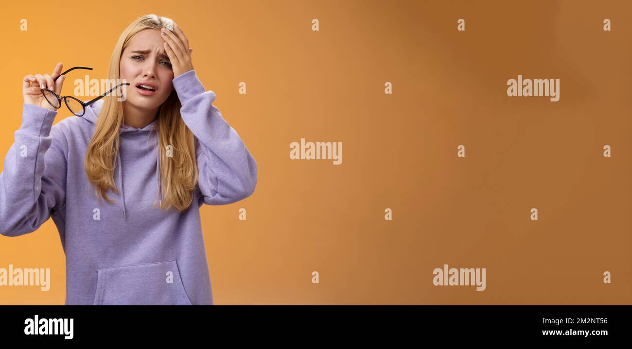 Upset gloomy bothered blond girl take-off glasses cringing grimacing ...