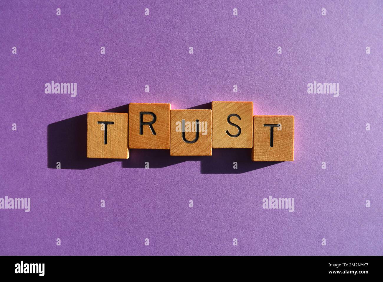 Trust, word in wooden alphabet letters isolated on purple background ...