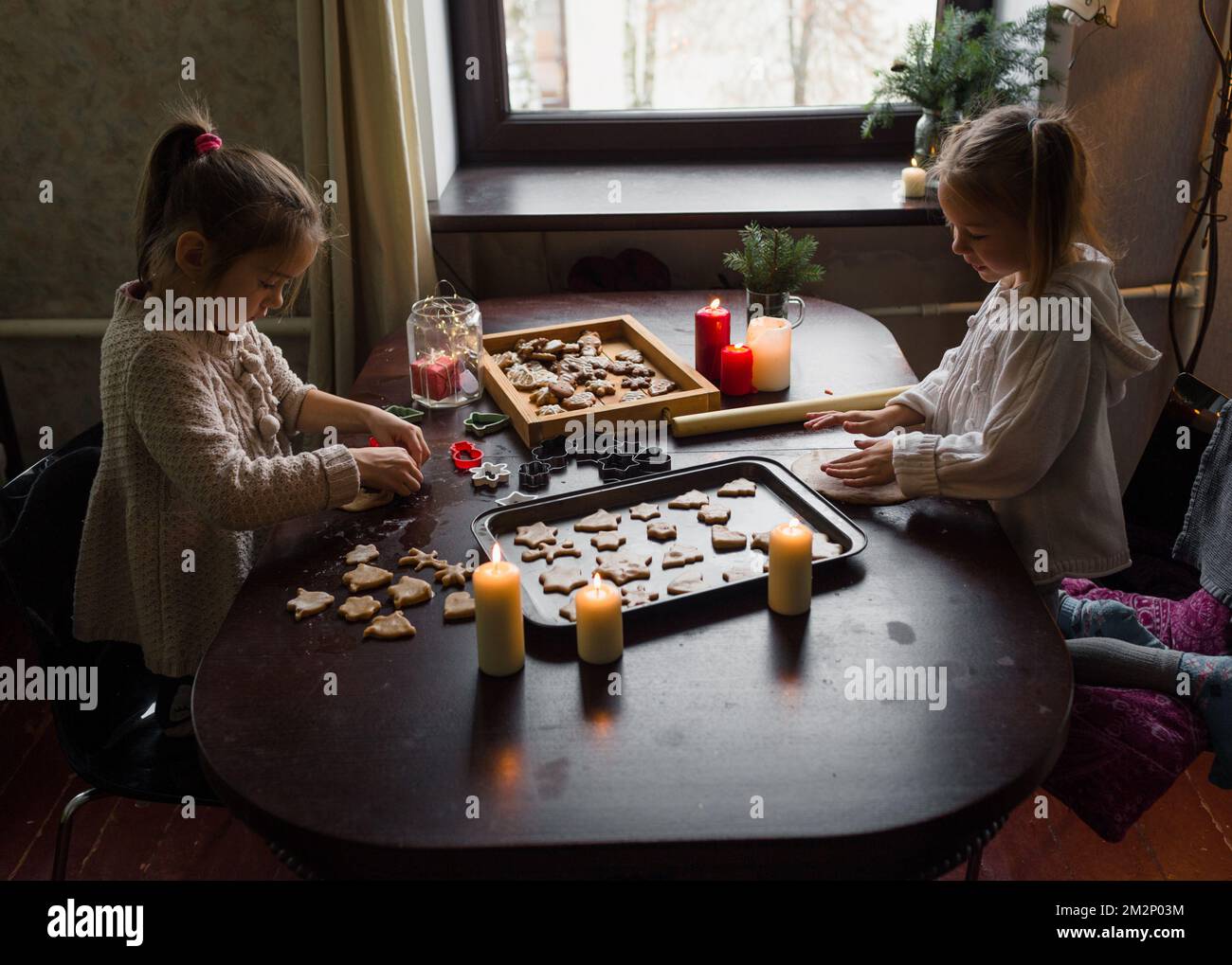 charming girls cook Christmas cookies together at home at the table ...