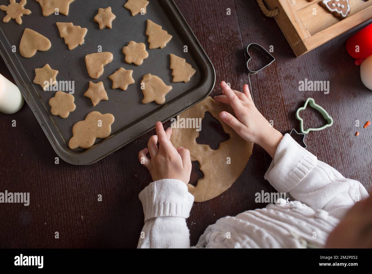 Child cuts cookies. Top view of kids hands with dough, rolling pin and ...