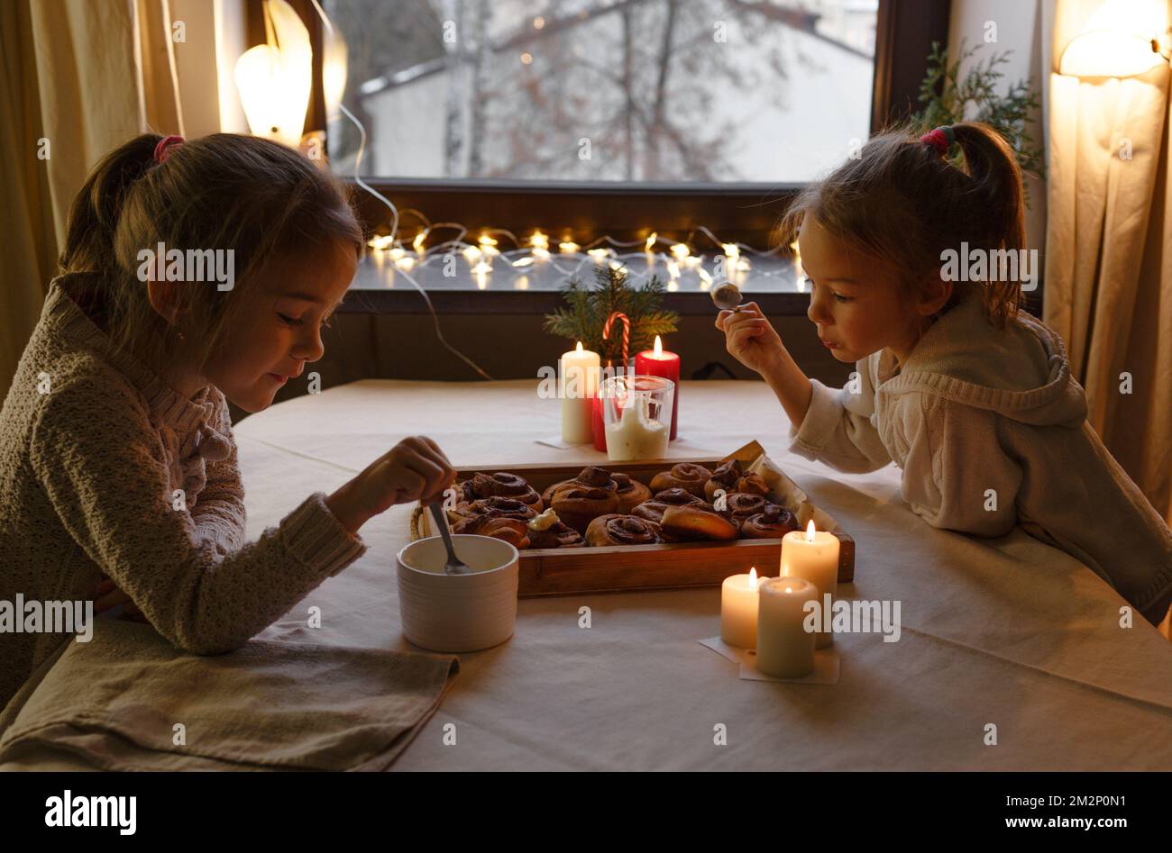Cute little girls are cooking Christmas gingerbread on a wooden table ...