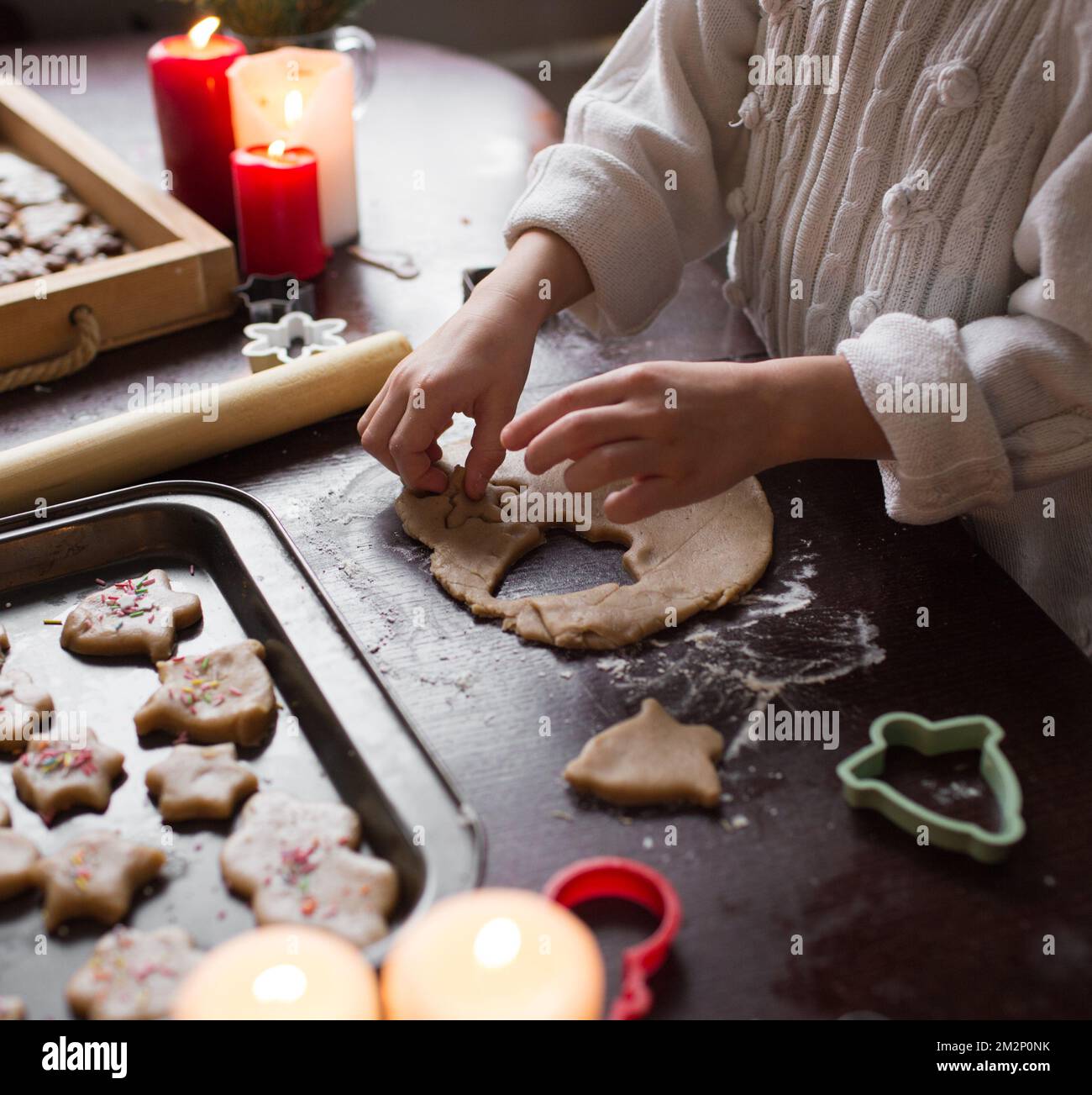 Child cuts cookies. Top view of kids hands with dough, rolling pin and ...