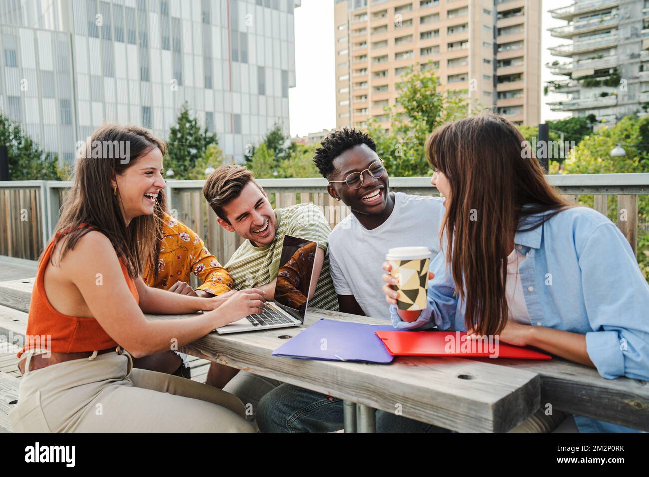 Multiracial smiling group of five teenagers students using laptop doing homework and enjoying a ...