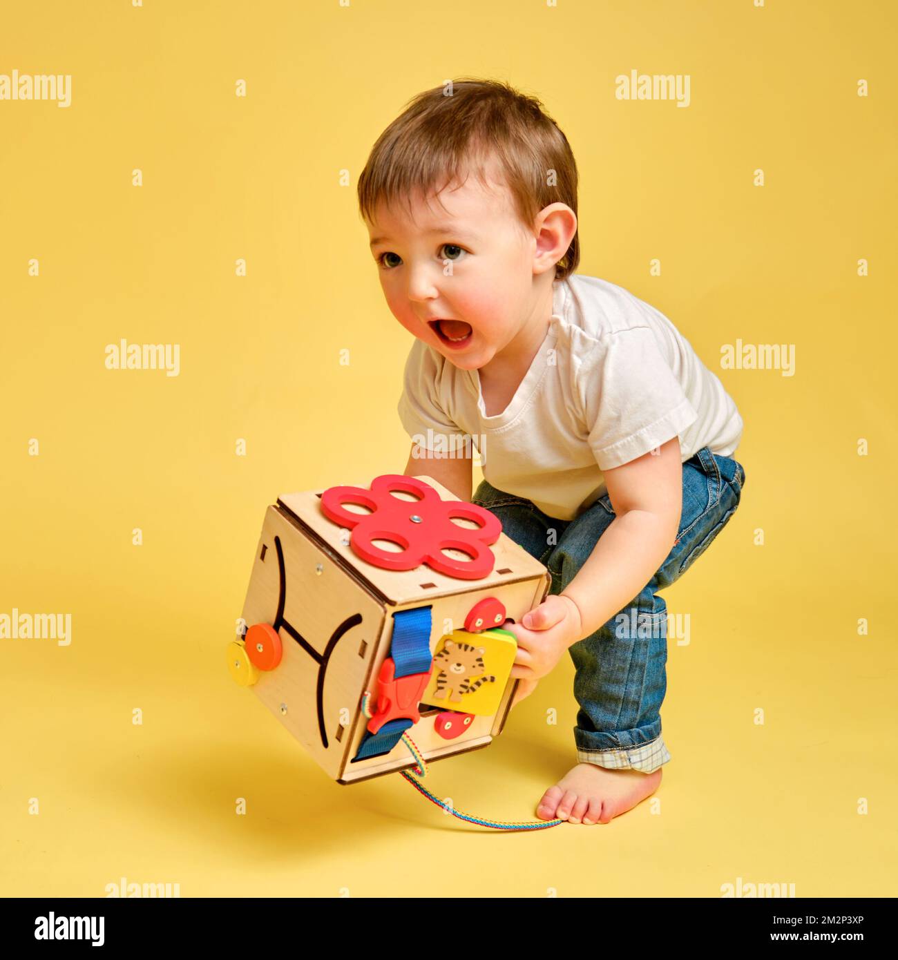 Toddler baby is playing logic educational games busyboard on a studio ...